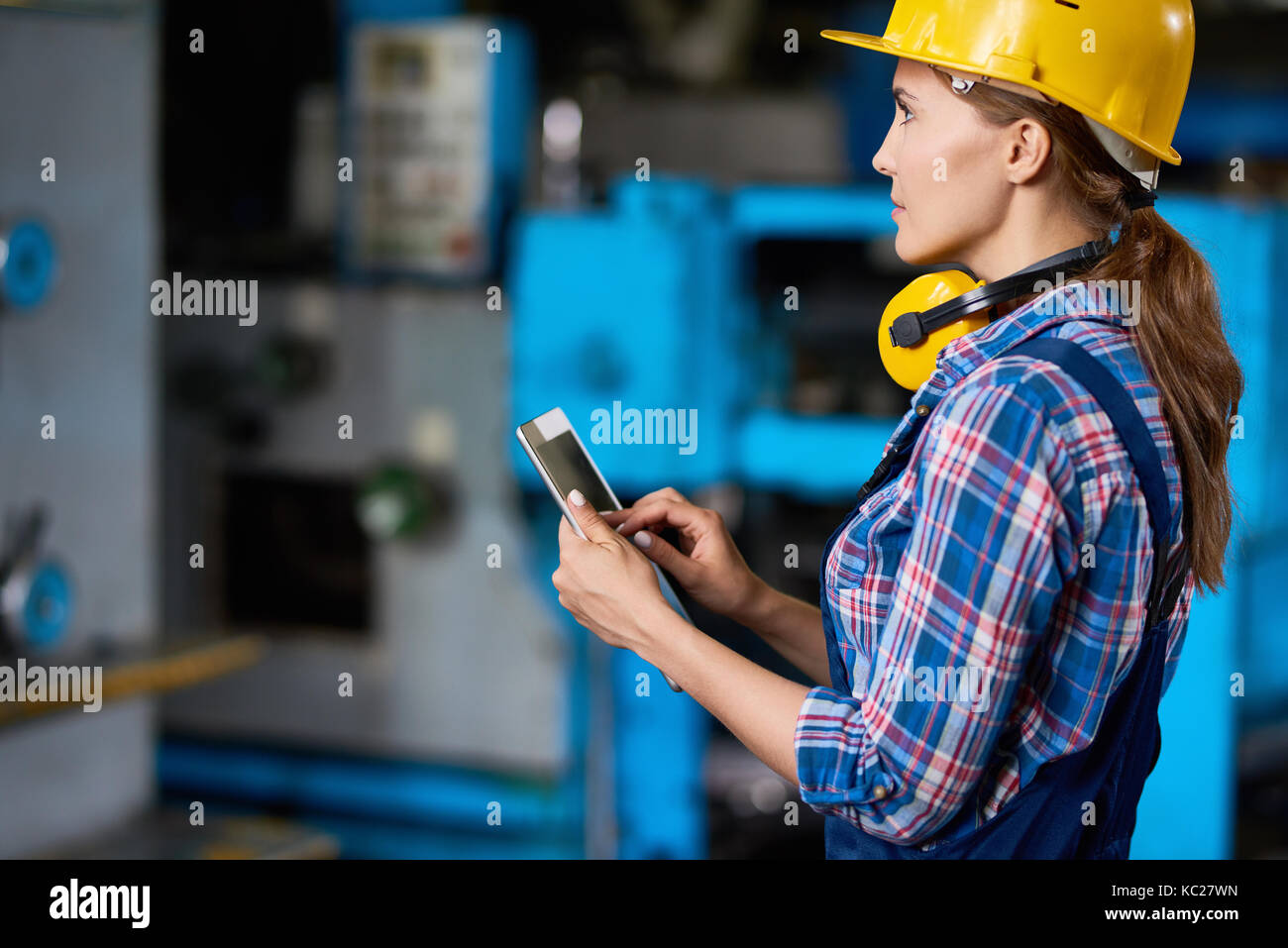 Side view portrait of female machine operator using digital tablet ...