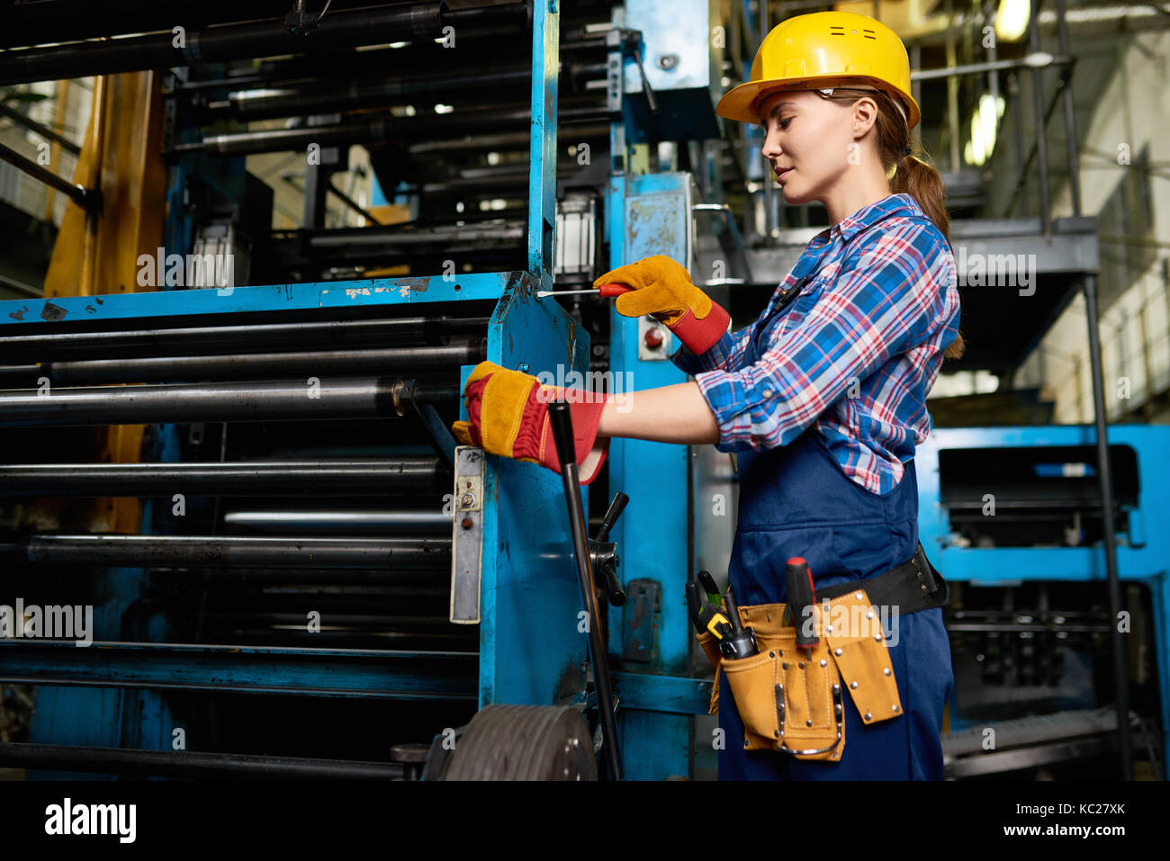 Side view portrait of female factory worker setting up machine units in ...