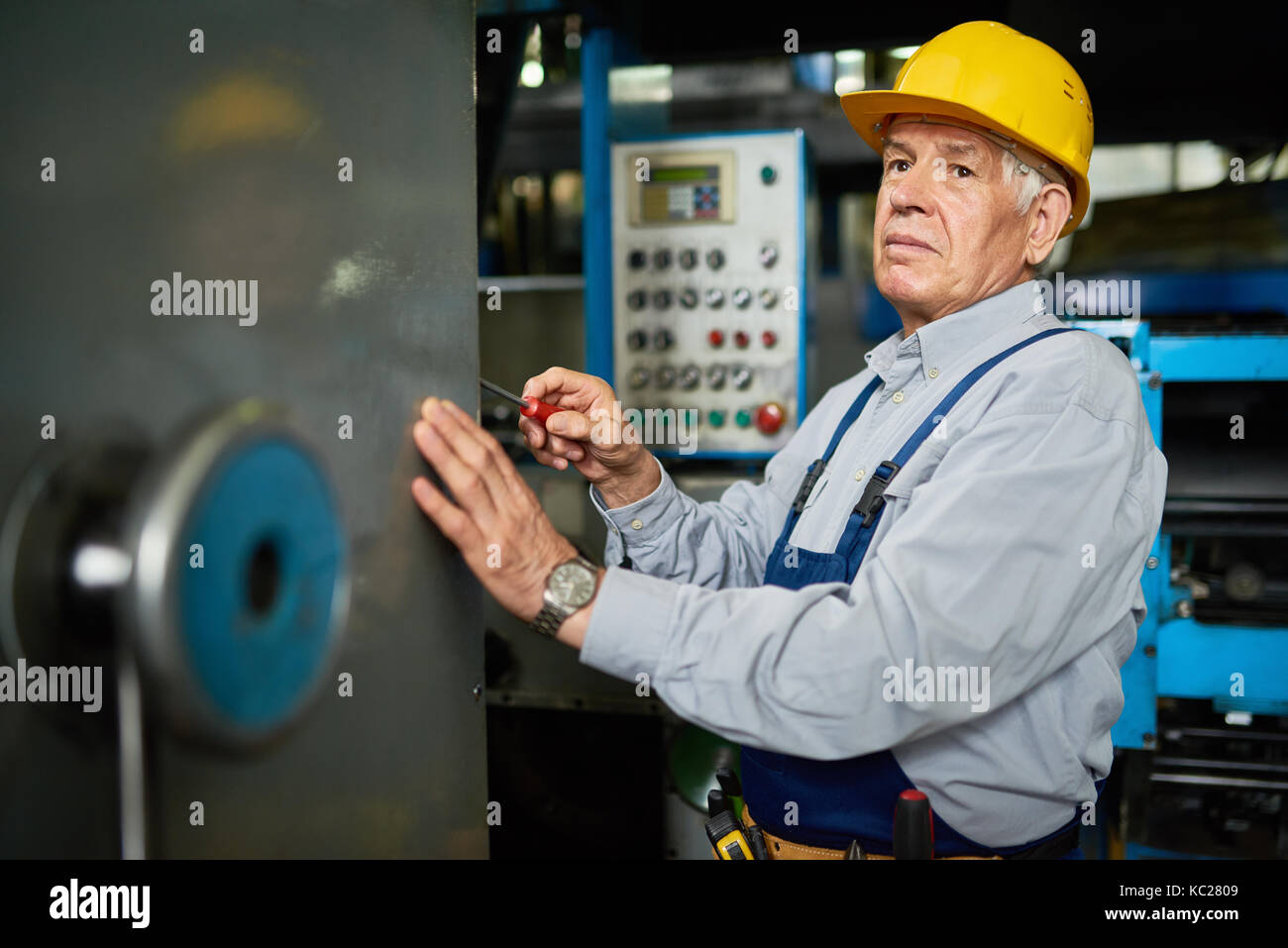 Portrait of senior mechanic repairing machine units in workshop of ...