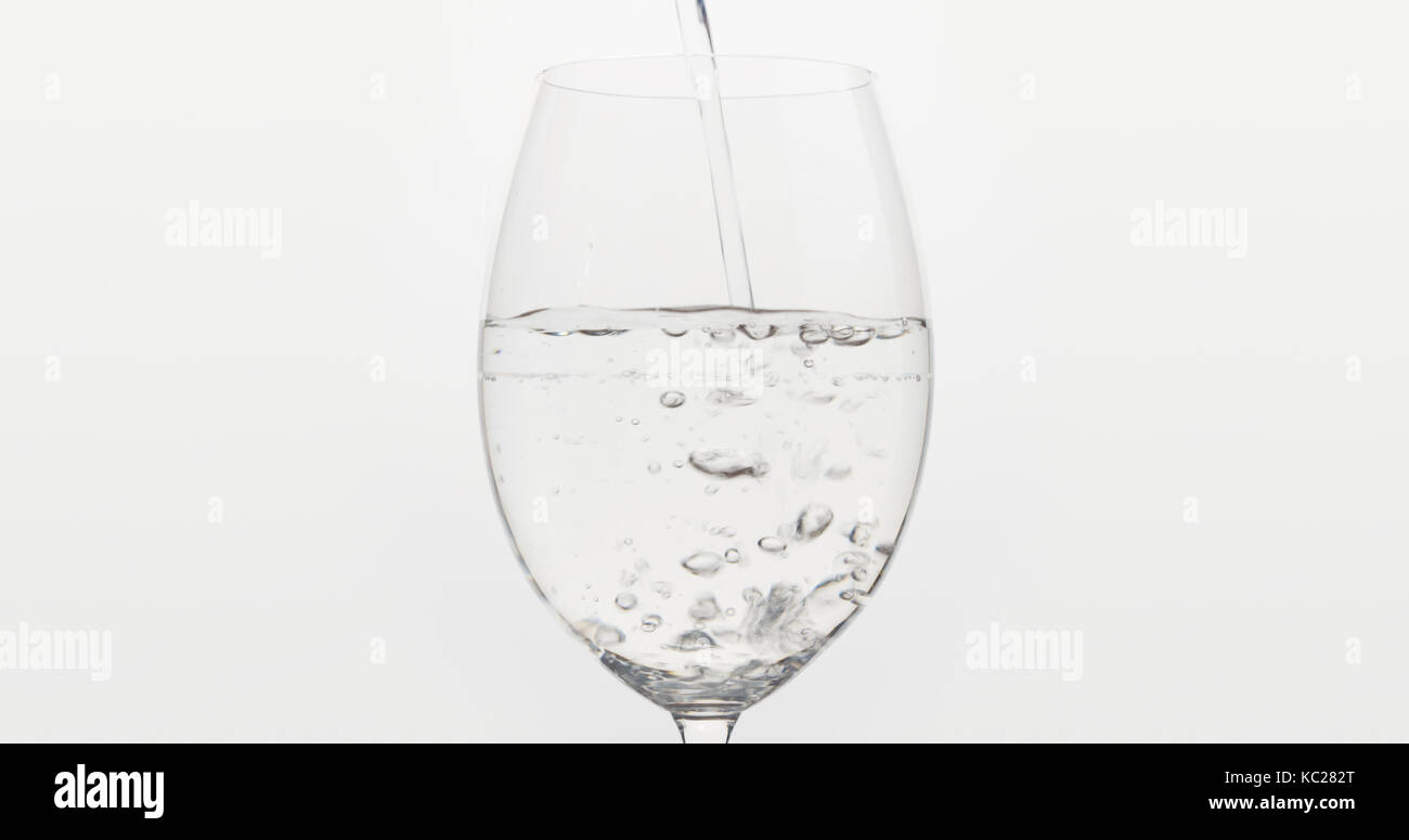 pouring water into wine glass over white background, wide photo Stock Photo - Alamy