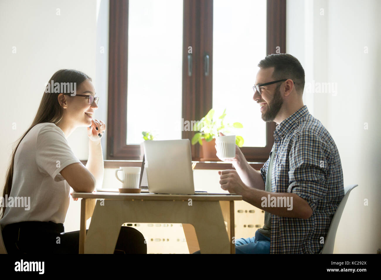 Two people working together on a project, talking and laughing ...