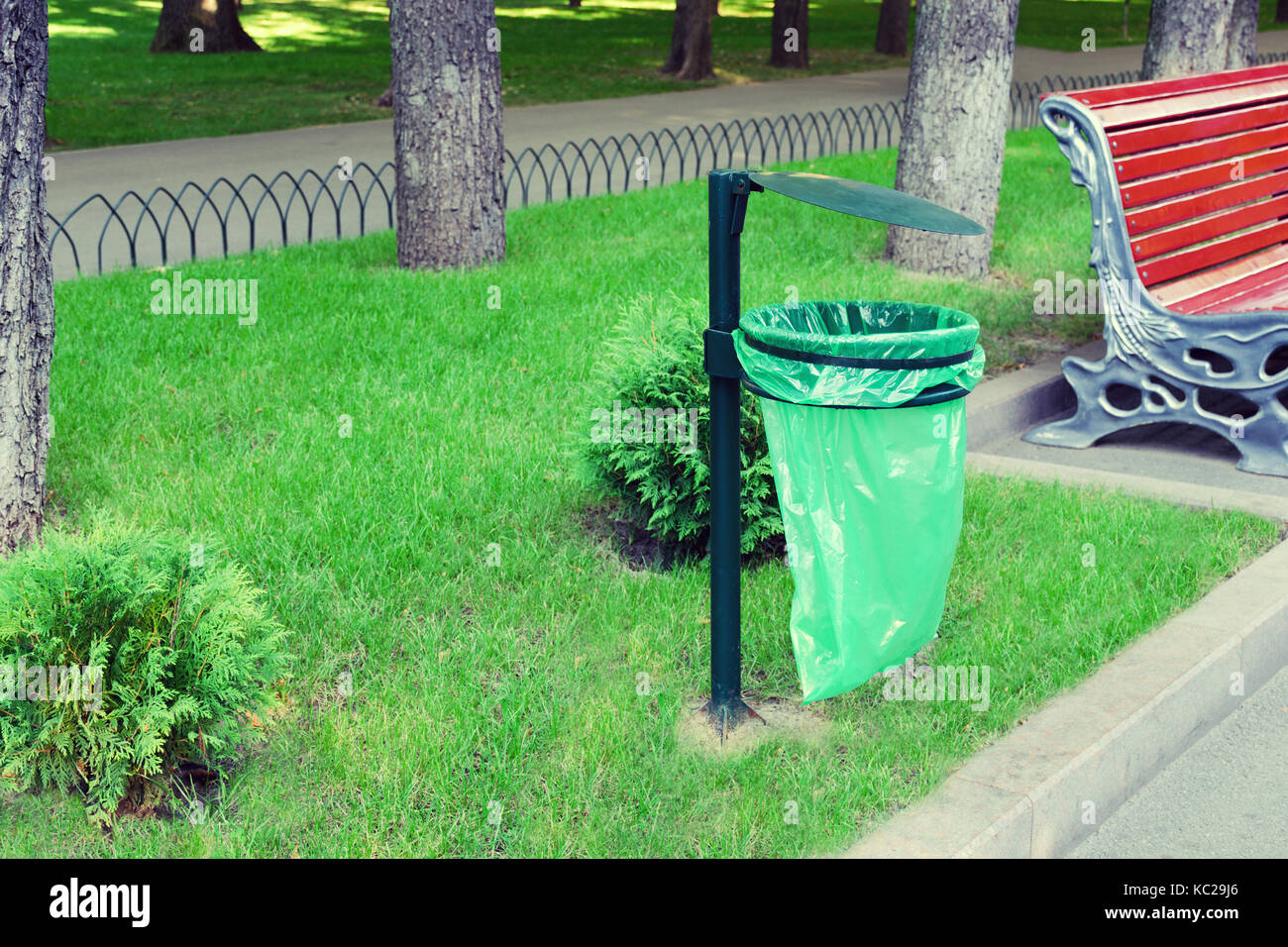Street waste basket with a plastic bag of green in the city park ...