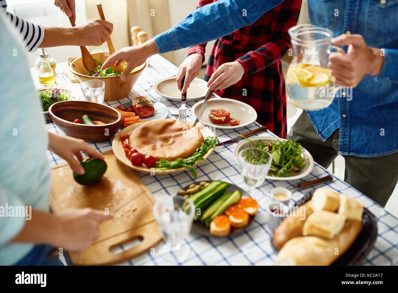 High angle closeup of group of people preparing dinner together ...