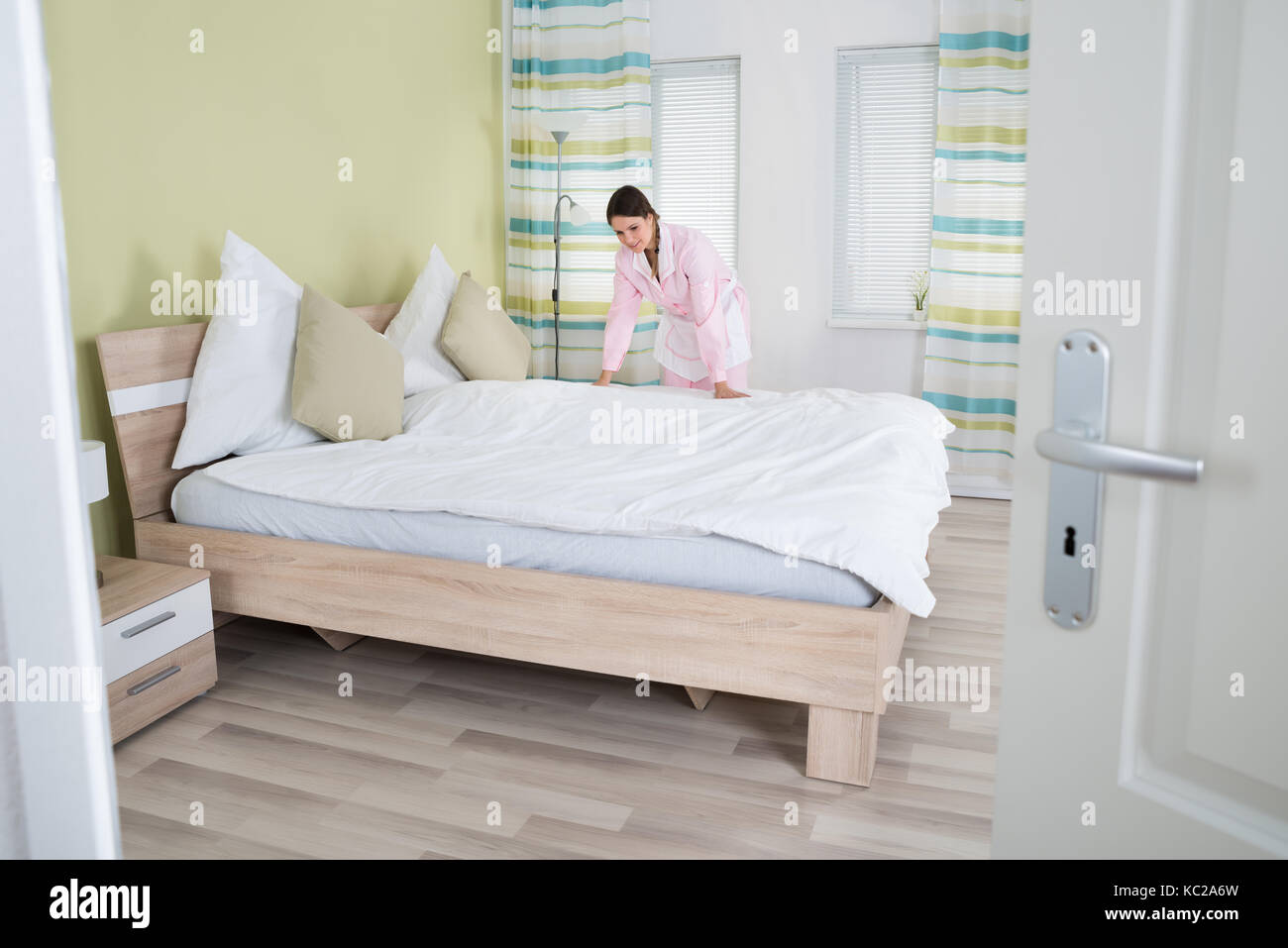 Young Female Housekeeper Making Bed In Room Stock Photo - Alamy