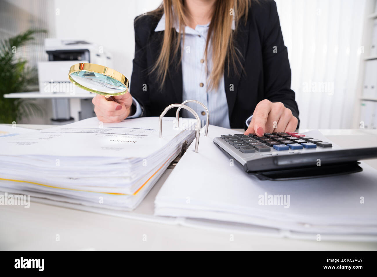 Young Businesswoman Checking Invoice With Magnifying Glass At Desk ...