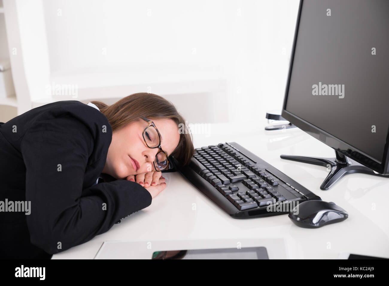 Young Businesswoman Sleeping On Desk In Office Stock Photo - Alamy