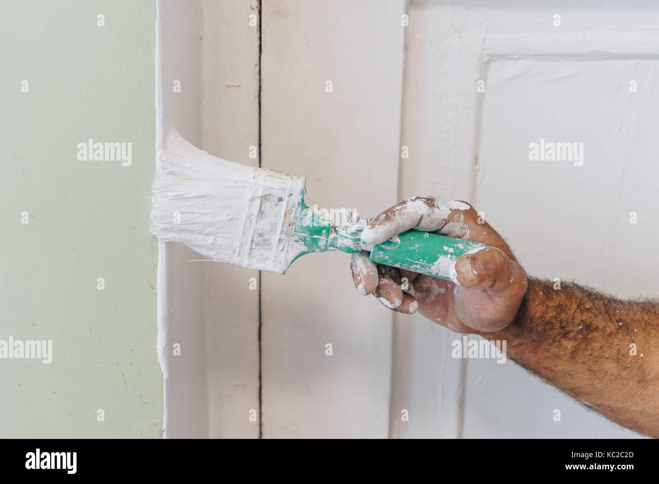 Mans hand painting wall in white Stock Photo - Alamy