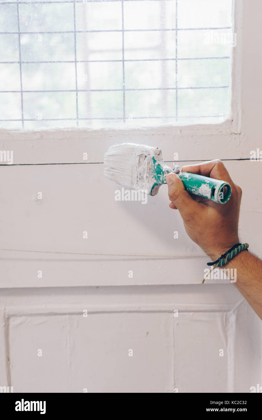 Mans hand painting wall in white Stock Photo - Alamy