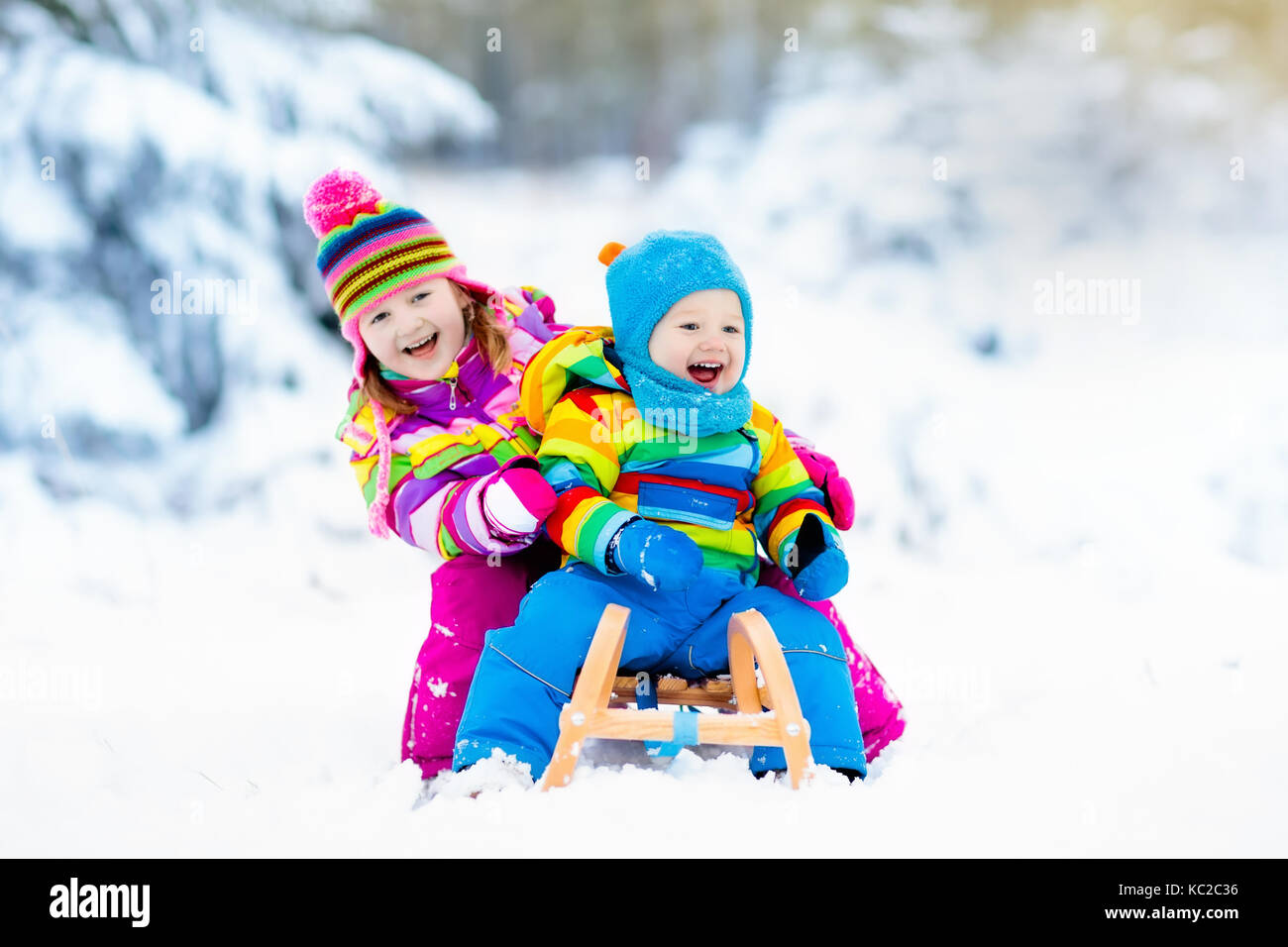 Little girl and boy enjoy a sleigh ride. Child sledding. Toddler kid ...