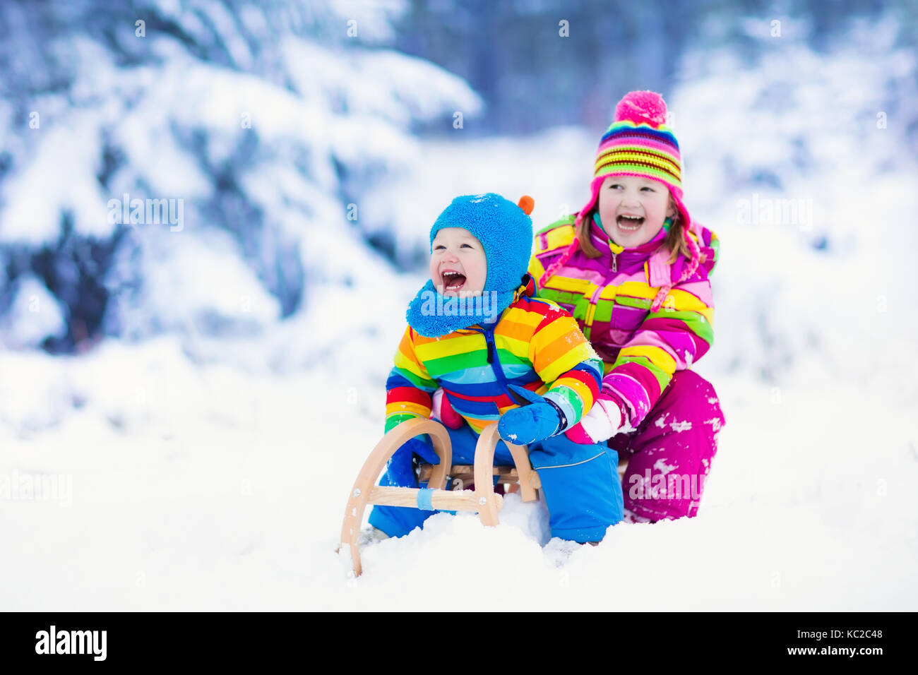 Little girl and boy enjoy a sleigh ride. Child sledding. Toddler kid ...