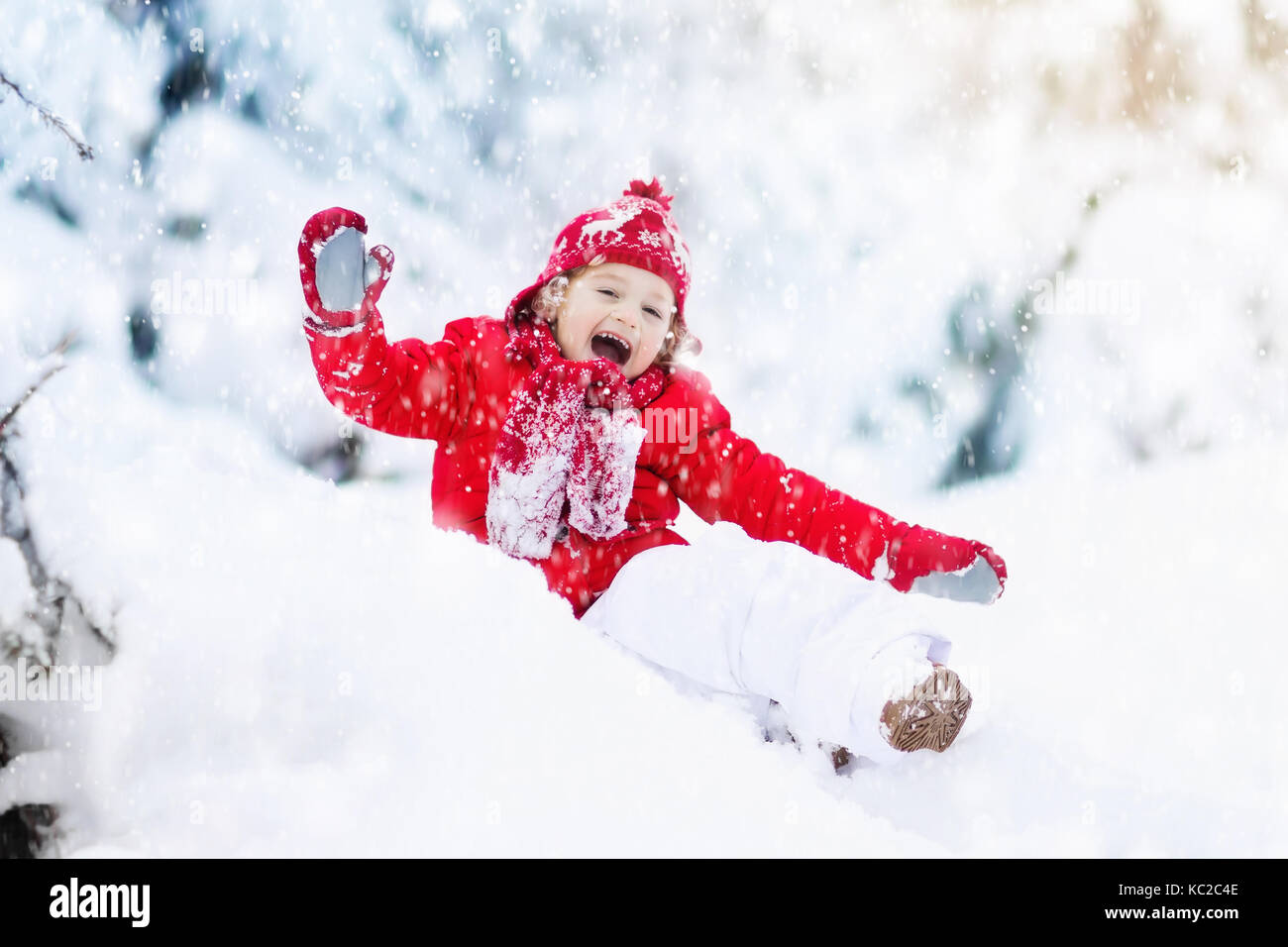 Child playing with snow in winter. Little boy in colorful jacket and ...