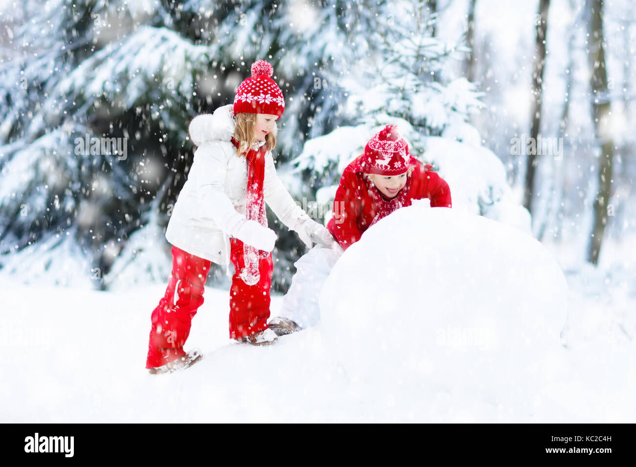 Children build snowman. Kids building snow man playing outdoors on ...