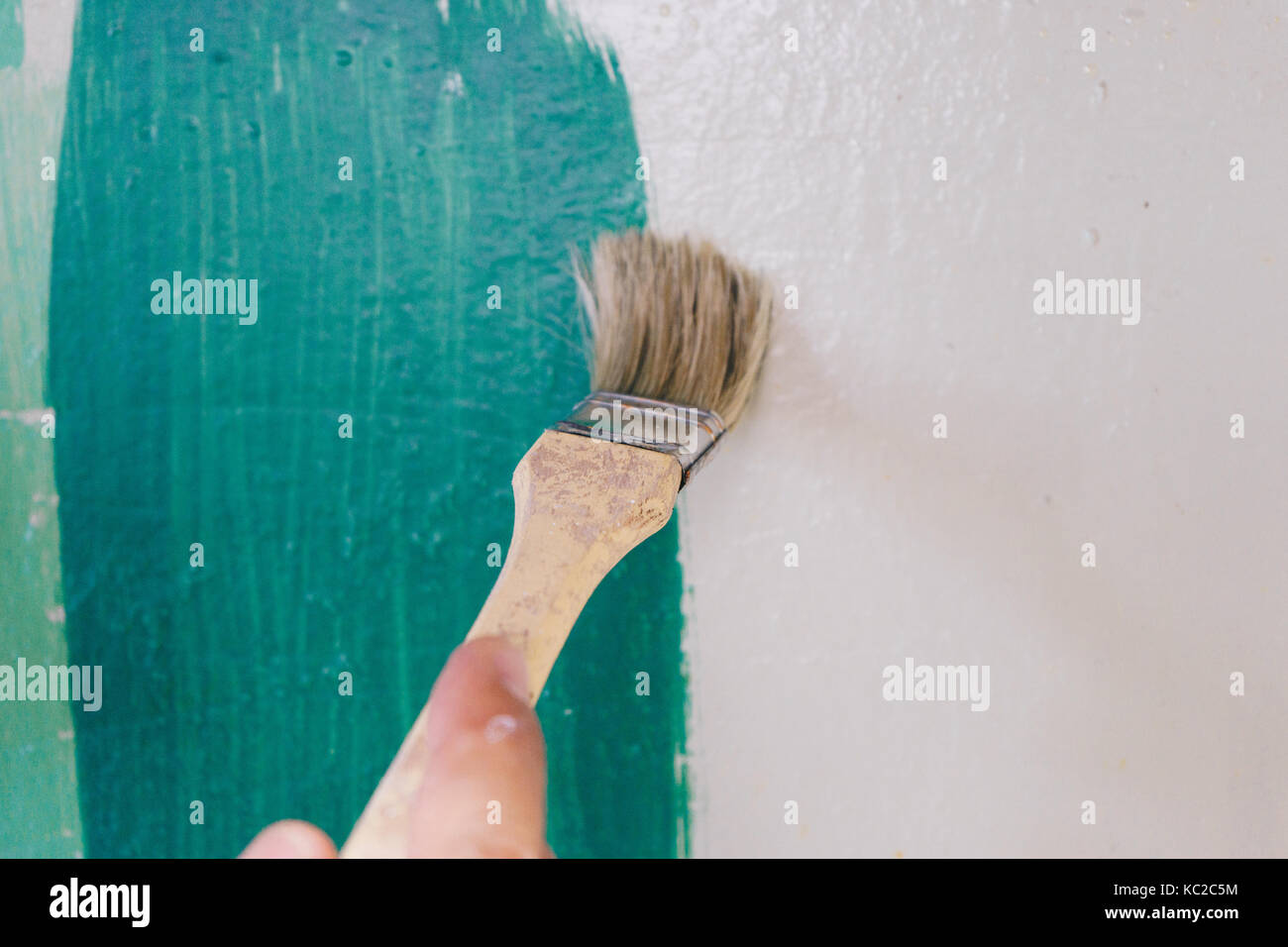 Mans hand painting wall in green Stock Photo - Alamy