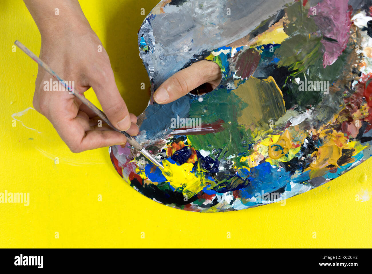 Artist is painting and mixing color tones on the pallet Stock Photo - Alamy