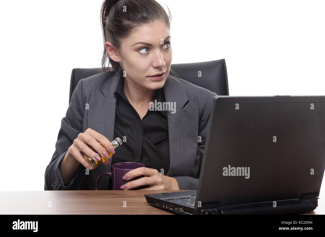 alcoholic business woman sneaking a drink at work sitting at her desk ...