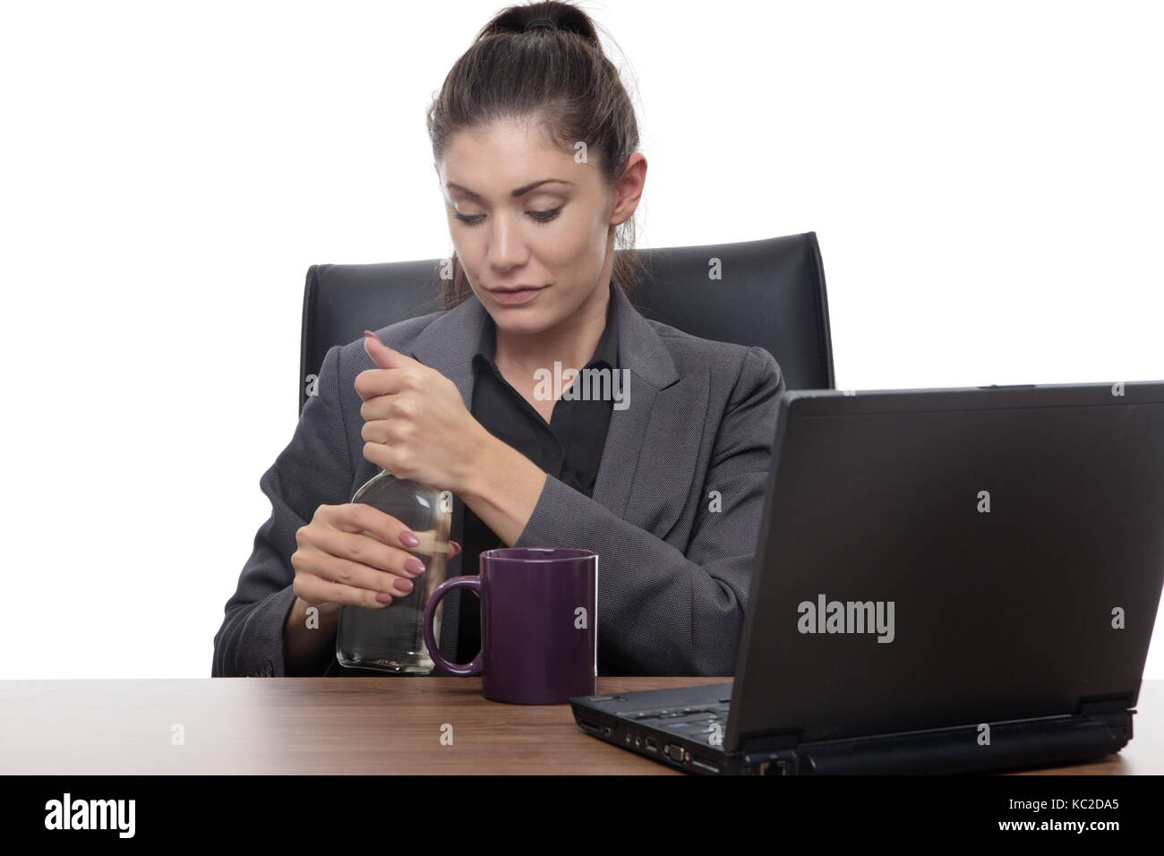 alcoholic business woman sneaking a drink at work sitting at her desk ...