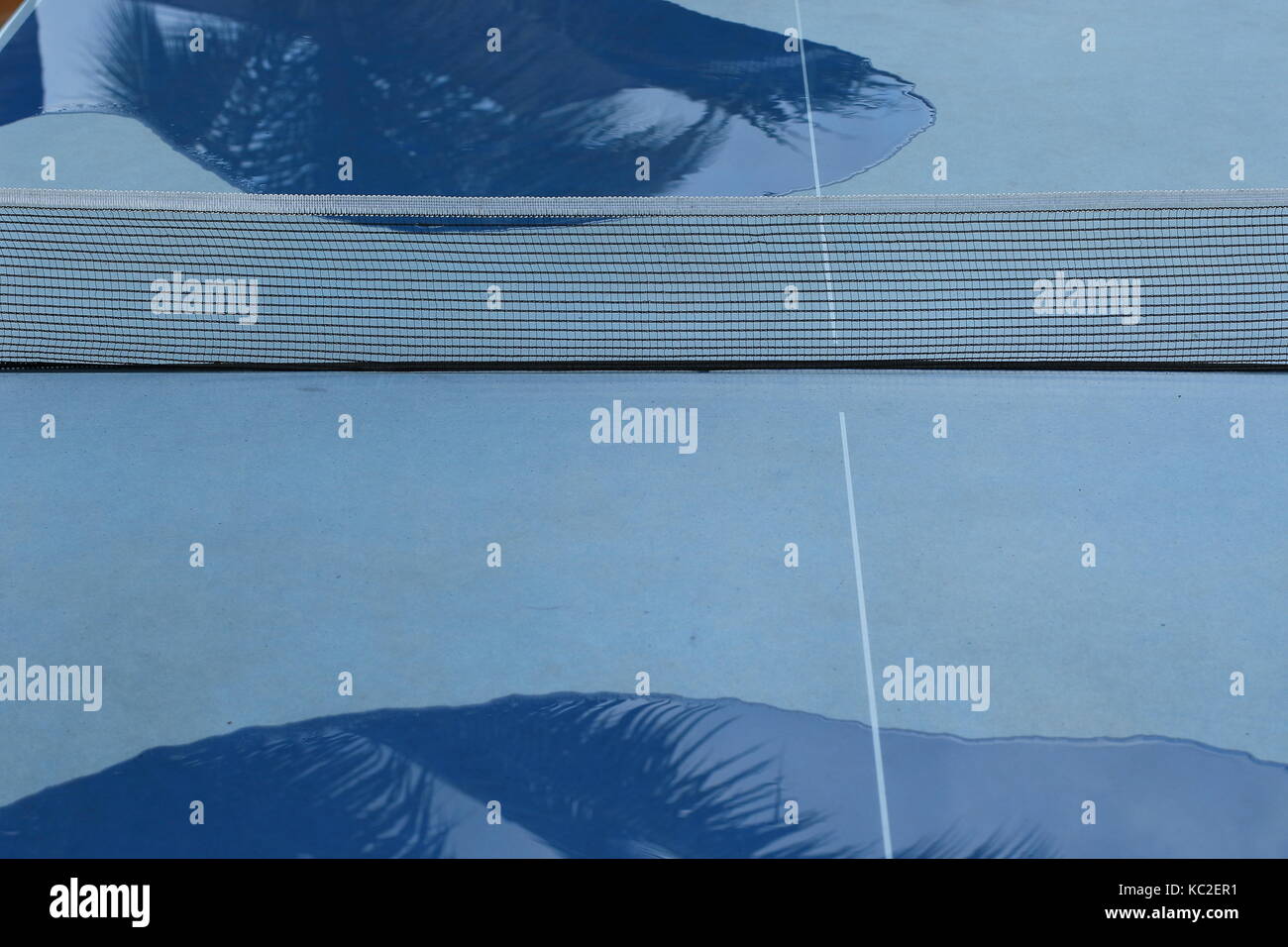 Abstract of a wet blue outdoor table tennis table with large puddles of ...