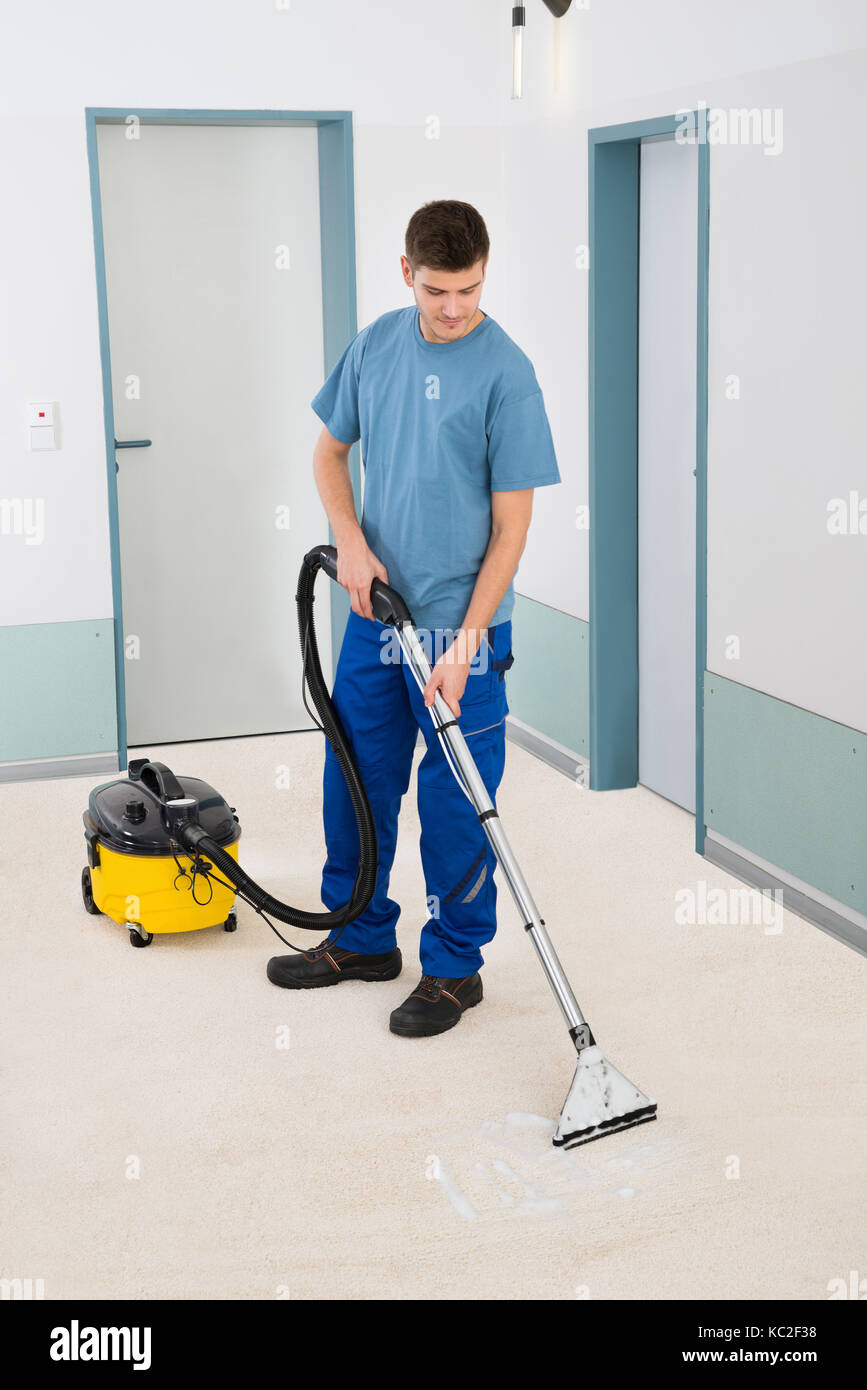 Young Male Cleaner In Uniform Vacuuming Floor Stock Photo - Alamy