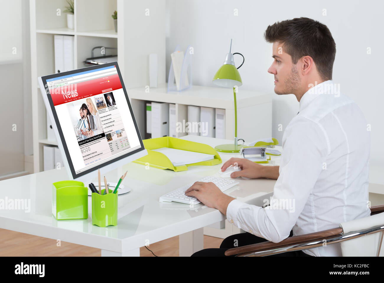 Young Businessman Watching Online News On Computer At Workplace Stock ...