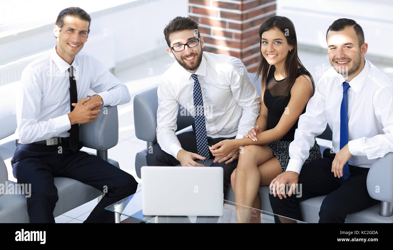 successful business team sitting in office lobby, in front of an open ...