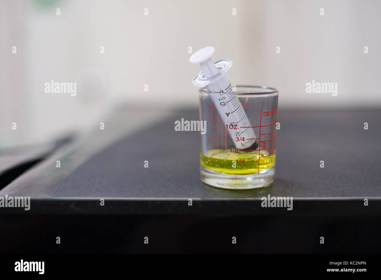 syringe with medicine syrup in a Pharmaceutical glass measuring cup for ...