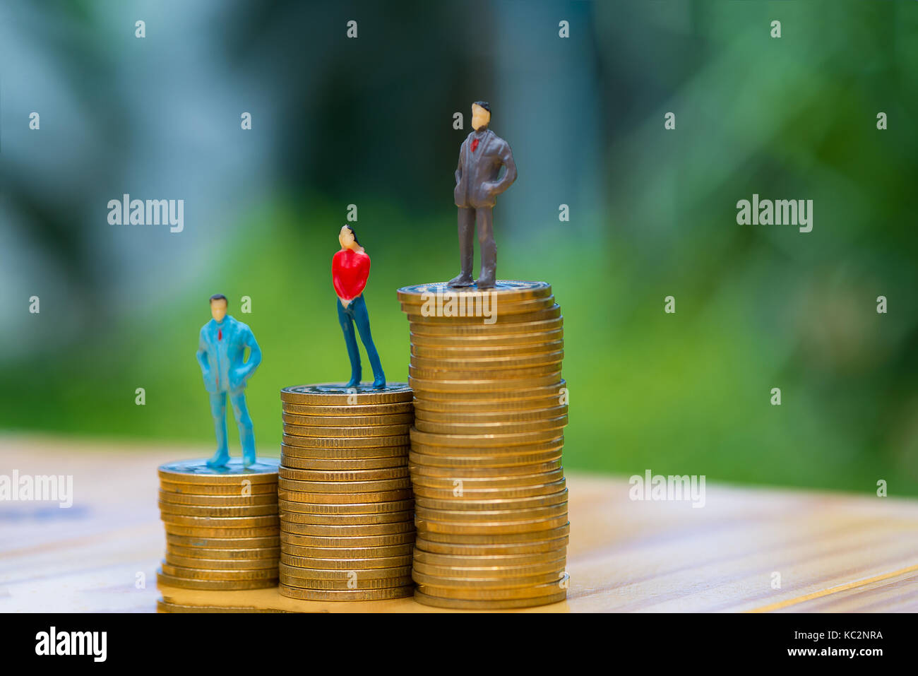 Miniature people, small figures businessmen and woman on top of coins ...