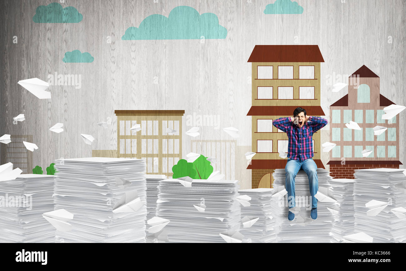 Young man sitting on pile of paper documents Stock Photo - Alamy
