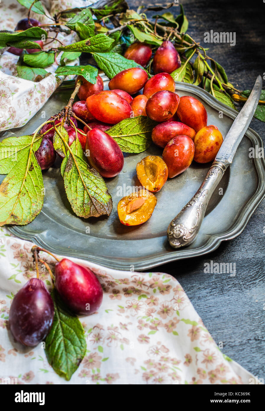 Fresh organic plums with leaves on old rustic wooden table Stock Photo ...