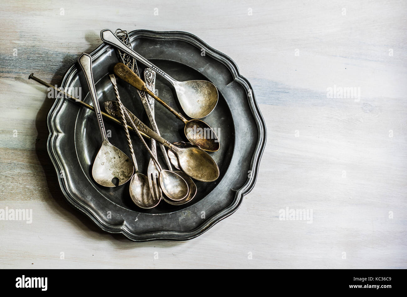 Vintage metal plate full of vintage silverware on rustic wooden table ...