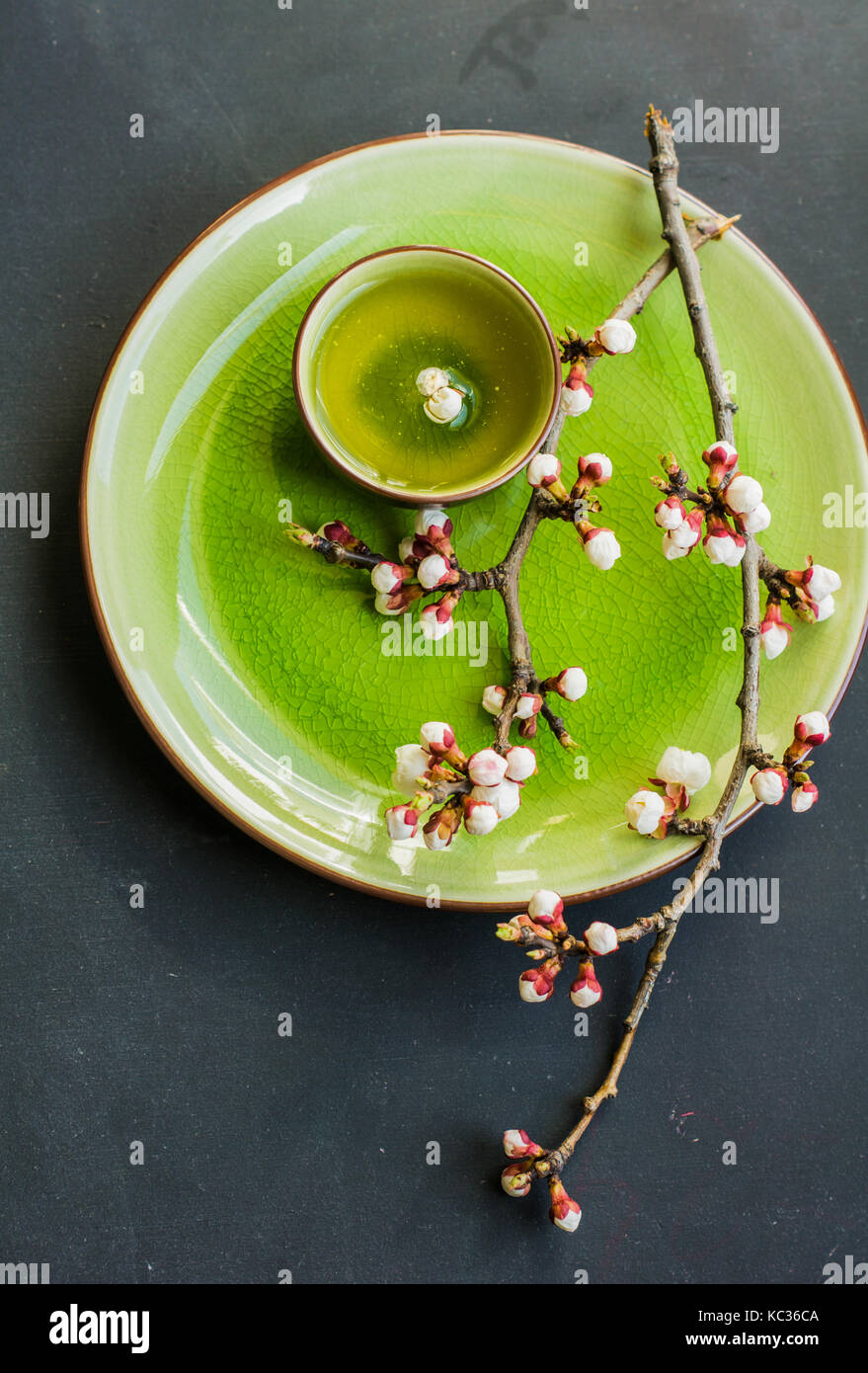 Cup of green tea and peach blossom on dark rustic table as a spring ...