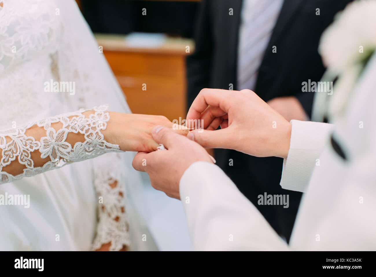 Groom`s hands putting the wedding ring on the finger of the bride Stock ...