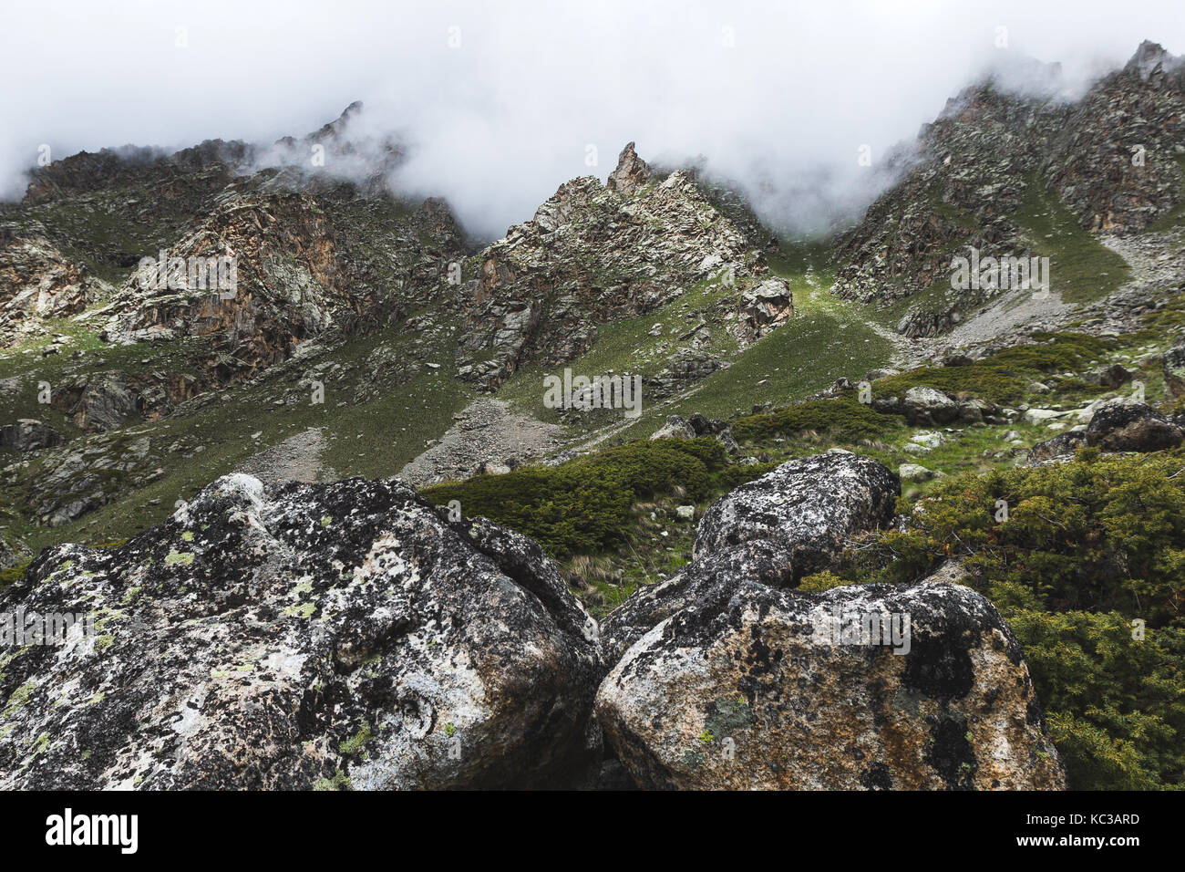 Mountain landscape with rocks and creeping fog. High peaks in the ...