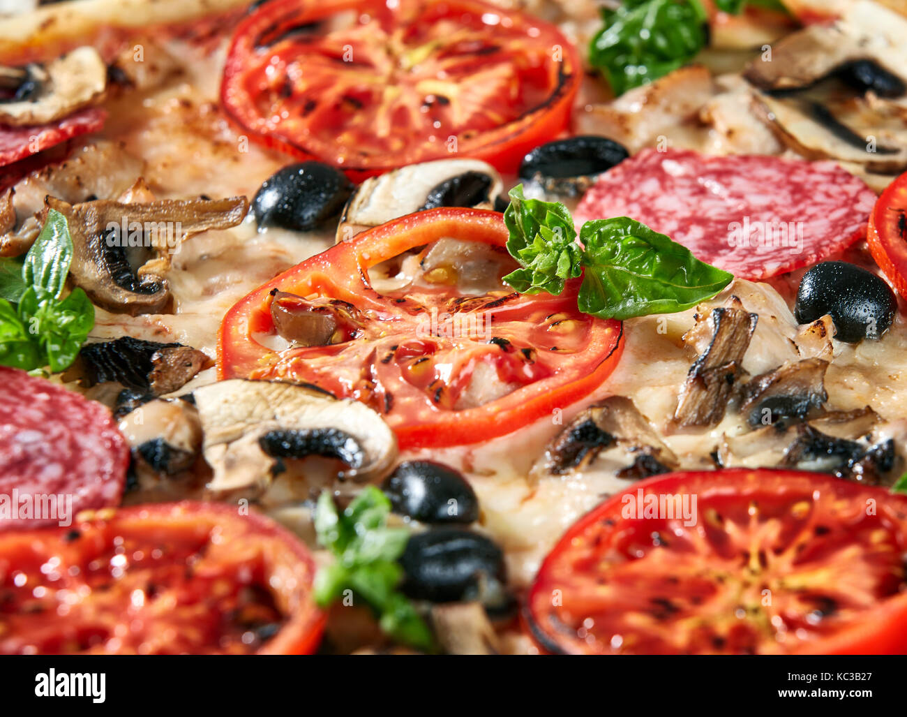 Closeup of pizza with salami, tomatoes and olives Stock Photo - Alamy