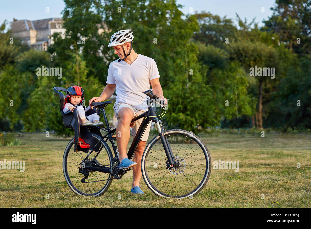 Cheerful family biking in park Stock Photo - Alamy