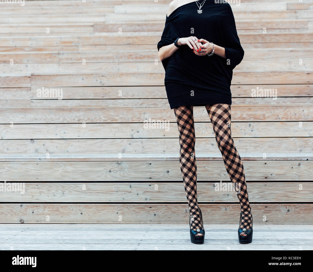 A long-legged girl in fashionable pantyhose, a black dress and black ...