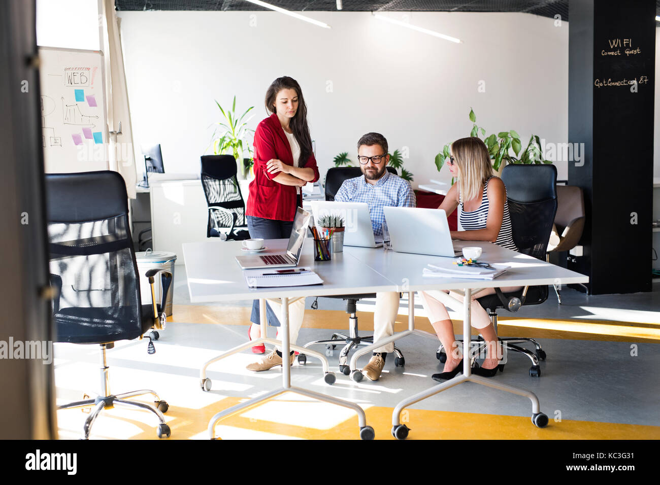 Three business people in the office talking together Stock Photo - Alamy