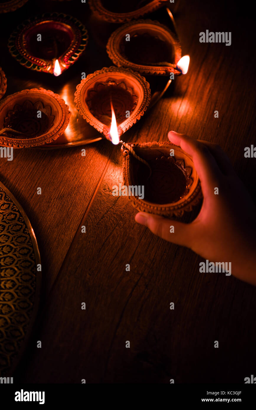 Happy diwali - Hand holding or lighting or arranging diwali diya or ...