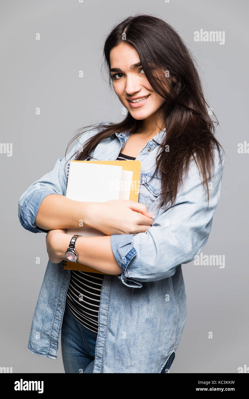 Portrait of happy student woman holding books against gray background ...