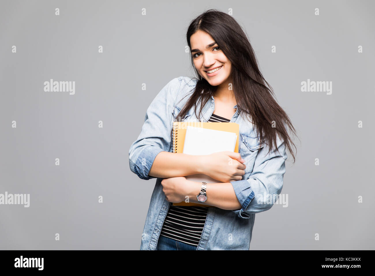 Portrait of student holding a book over grey background Stock Photo - Alamy