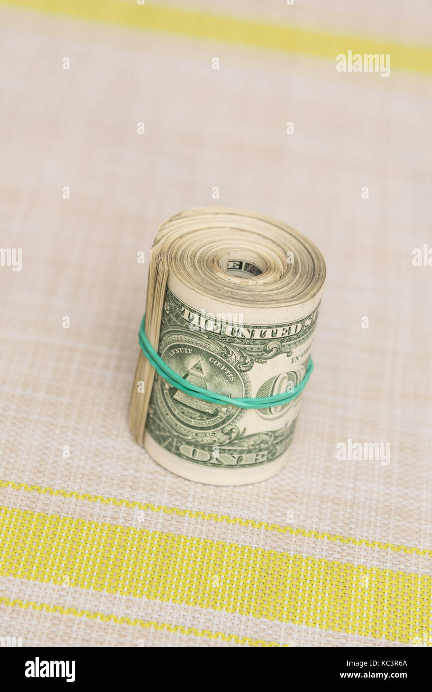 A bundle of money twisted into a bundle and bound by a green rubber ...
