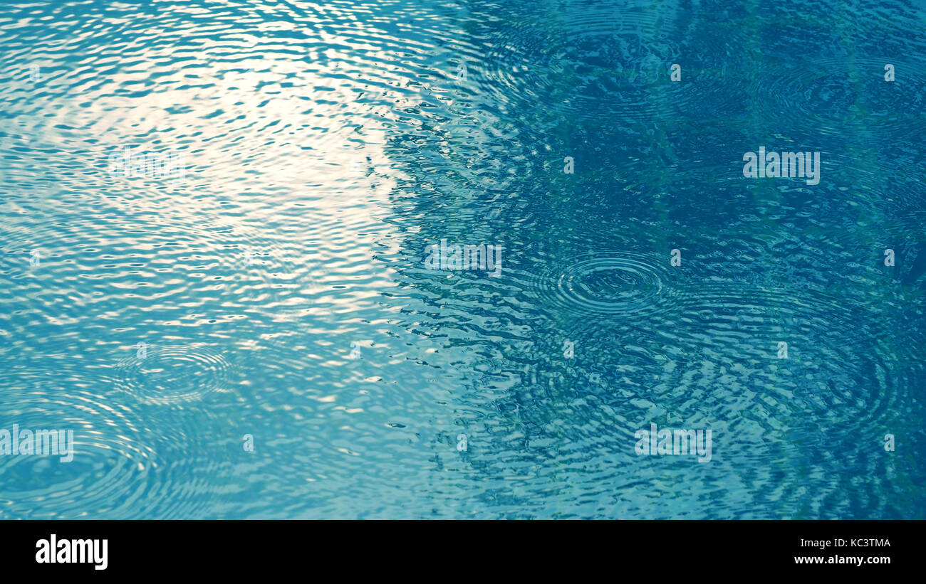 Rain drop on the surface of swiming pool water and have a ripple wave ...