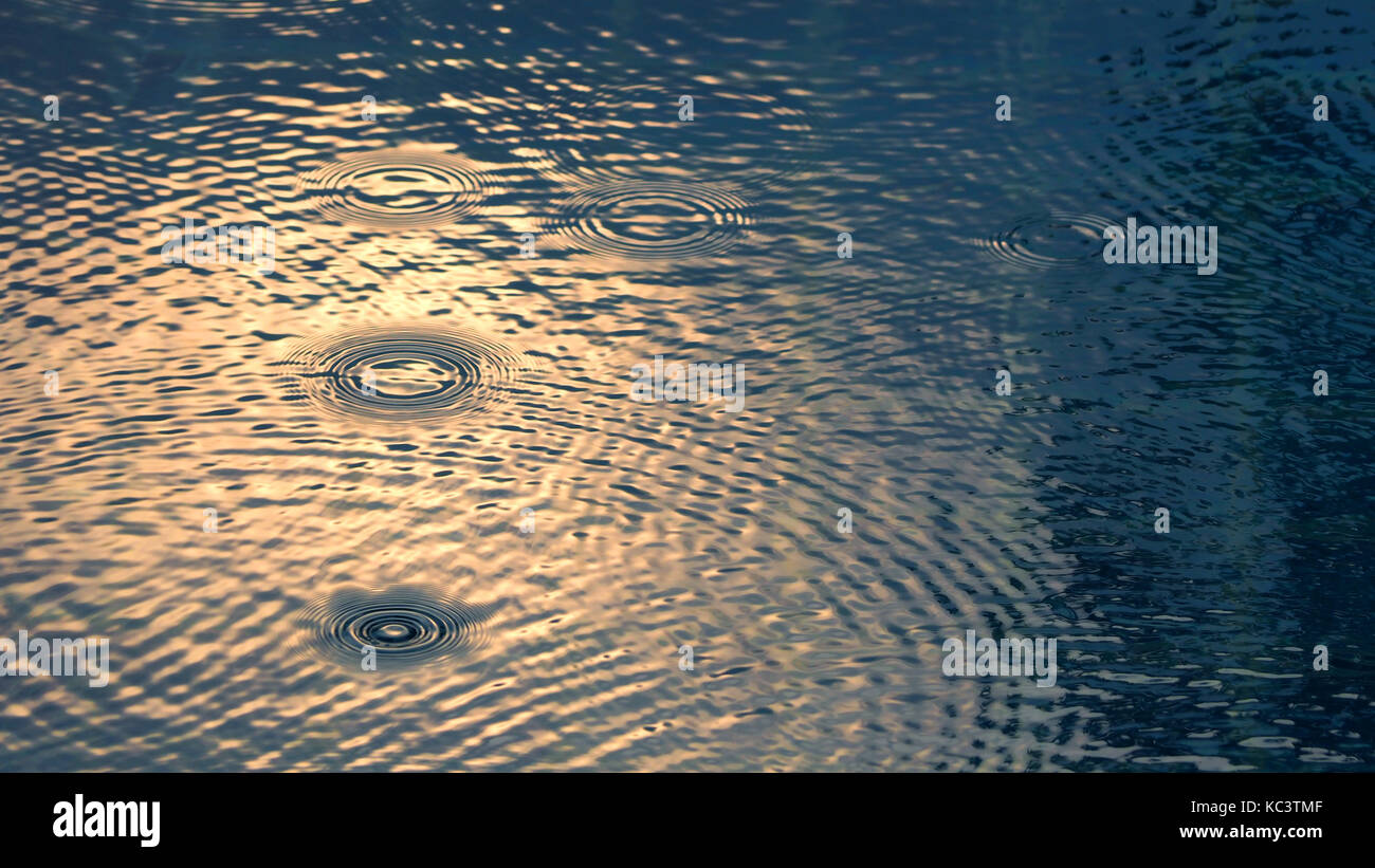 Rain drop on the surface of swiming pool water and have a ripple wave ...