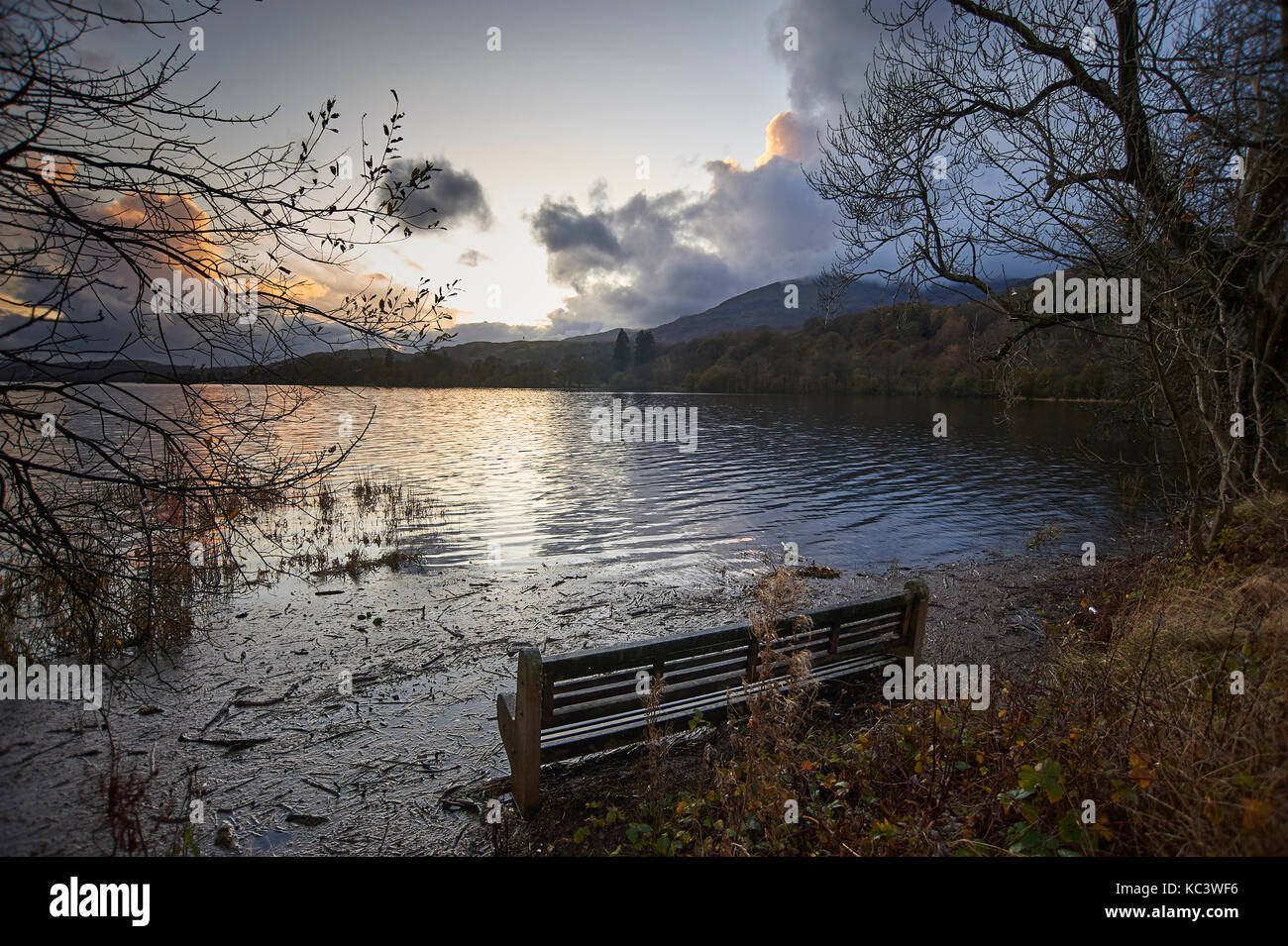 Park bench at flood water's edge of Coniston Water at sunset, Lake ...