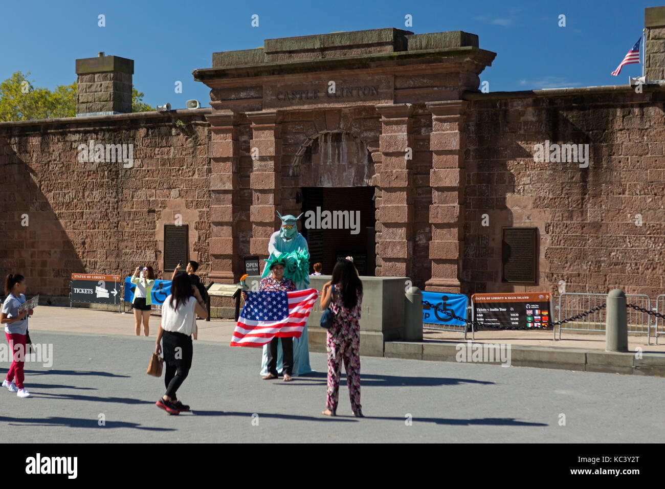 A performer dressed as the Statue of Liberty speaks with tourists ...