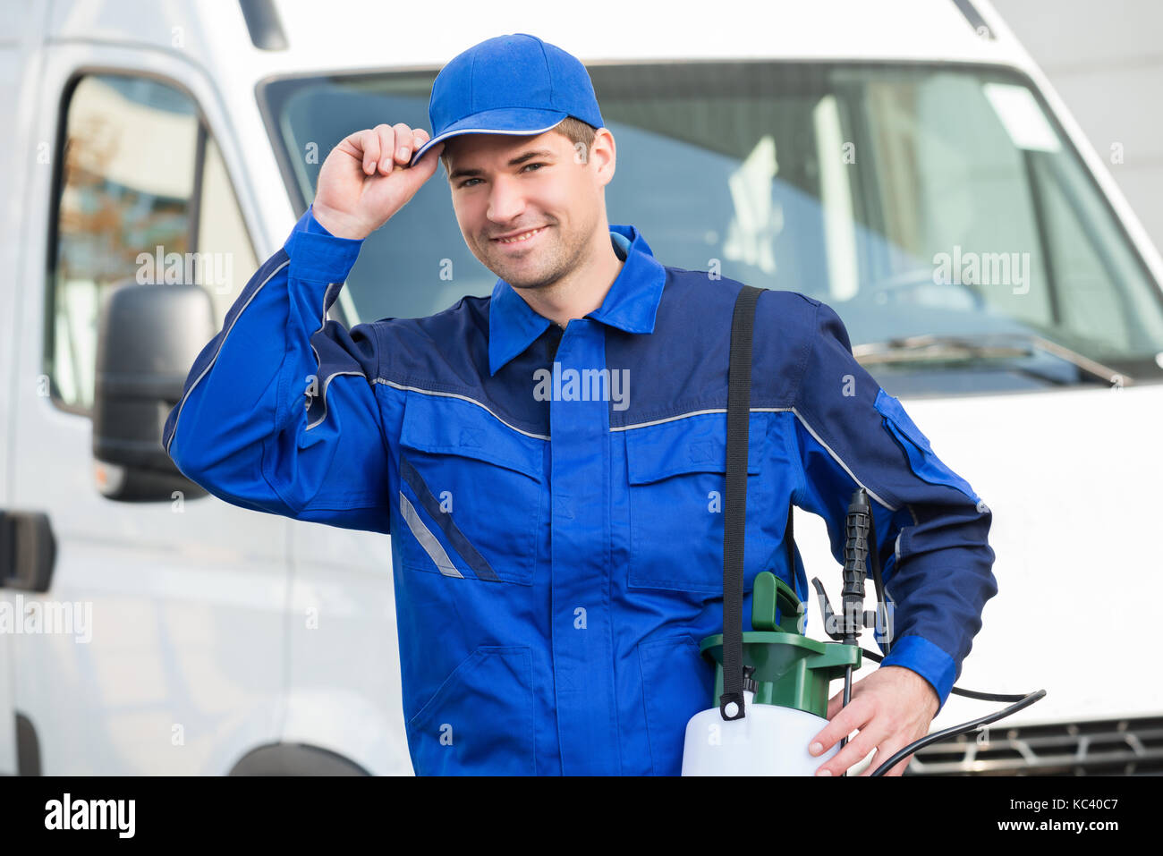 Portrait of confident pest control worker wearing cap against truck ...