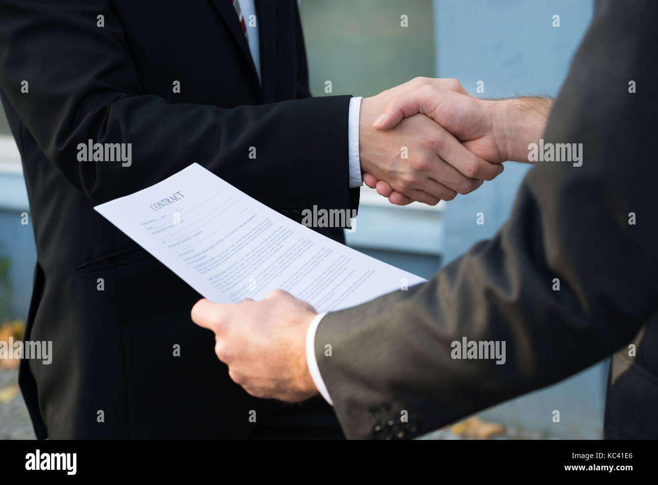 Cropped image of businessman shaking hands with partner while holding ...