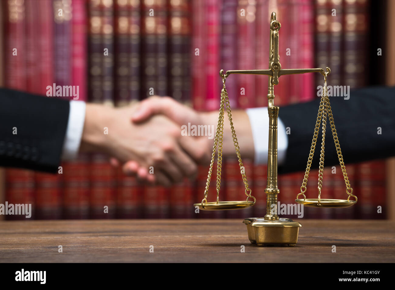 Justice scale on wooden table with judge and client shaking hands in ...