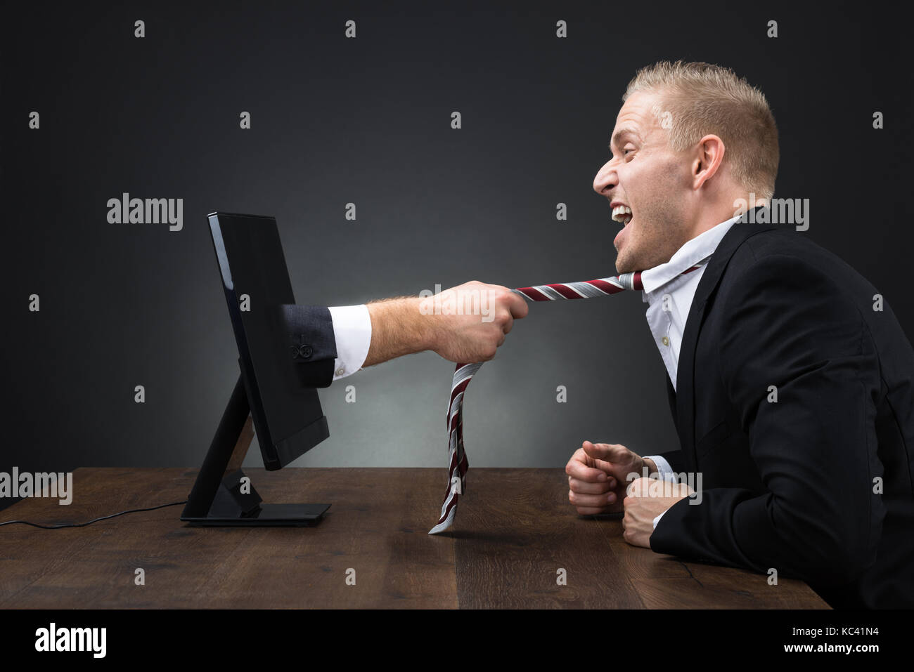 Businessman's hand emerging from computer monitor and pulling tie of ...