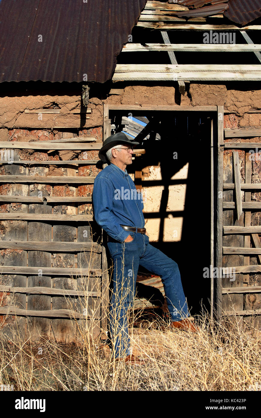 Man leans against dilapidated doorway of an old adobe in New Mexico ...
