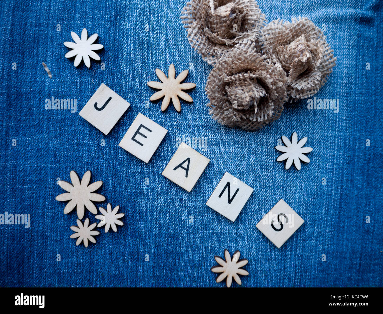 The word "Jeans" spelled out with wooden letter tiles on denim fabric ...